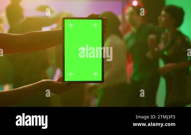 Woman holding greenscreen tablet at club and showing isolated display ...