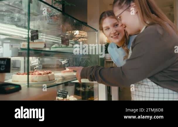 Zoom in of down syndrome girl advising client which cake to choose ...