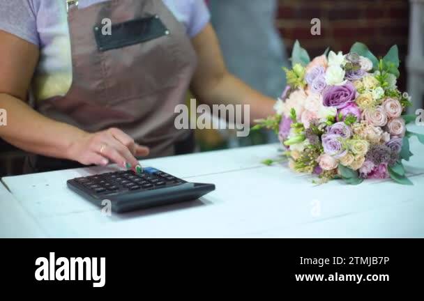 Female florist counting cost of bouquet with calculator in a flower ...