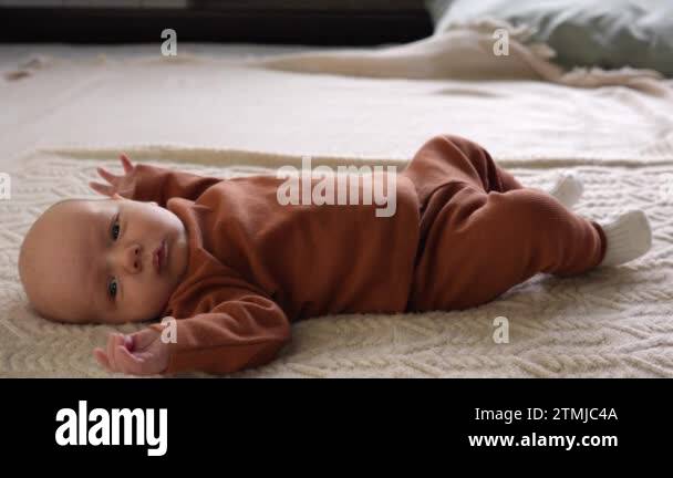 A little boy lies on the bed and looks away. Side view, slow motion. A ...