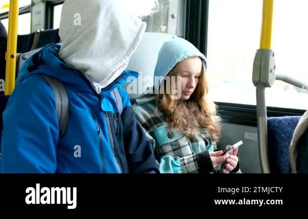 two teenagers in blue clothes sit on bus Canada Vancouver hoods autumn ...