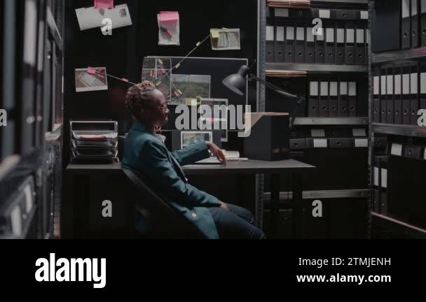 African american police investigator reading case file in incident room ...