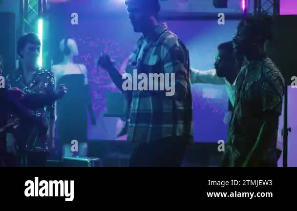 Young adults moving at disco party, having fun with stage lights and ...