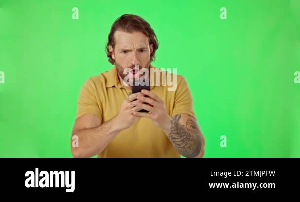 Face, green screen and man with smartphone, frustrated and angry ...
