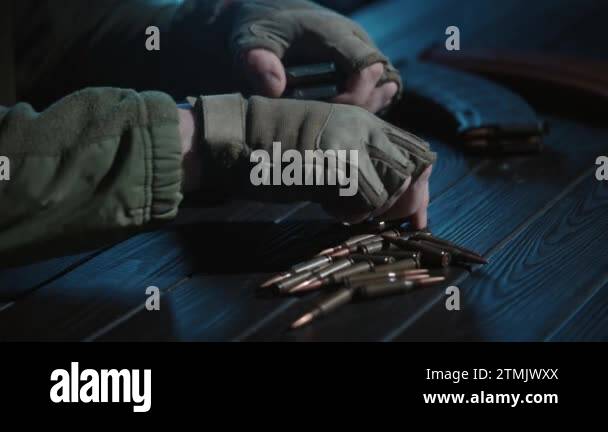 Male hands insert cartridges into the magazine of a assault rifle. Side ...