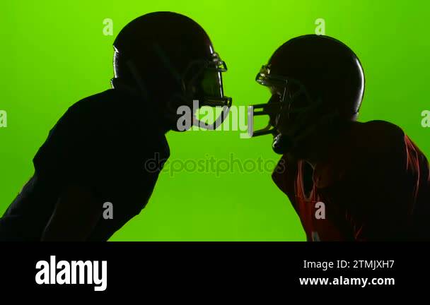 Two rugby players faced helmets in battle. Green screen. Slow motion ...