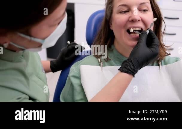 Dentist hand holding teeth color samples helping patient to choose ...