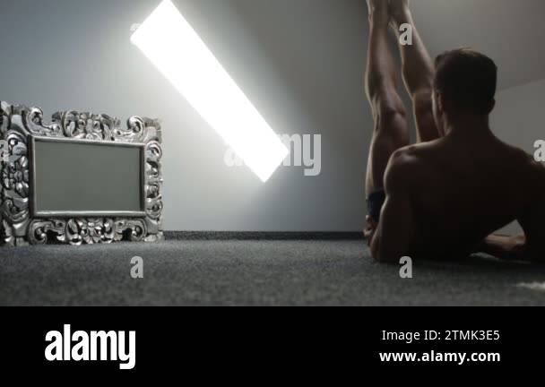 Bodybuilder doing workout with sit ups in front of a white wall and a mirror on the floor Stock ...