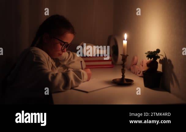 Schoolgirl uses candlelight to writes and reads in darkness without ...