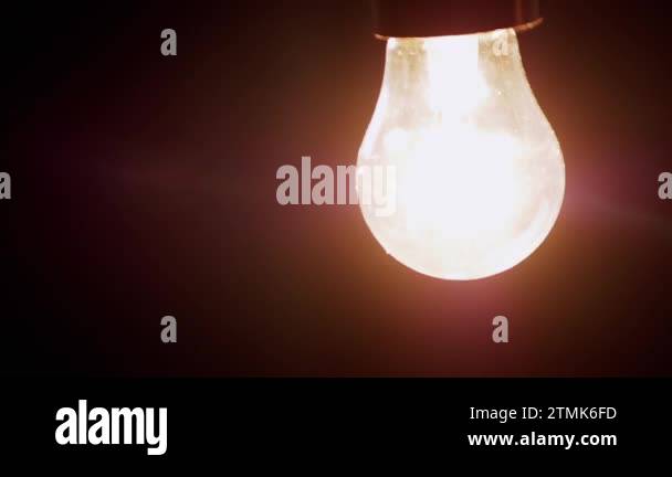 Hanging Swinging flickering Light Bulb in a Dark Room on the Black ...