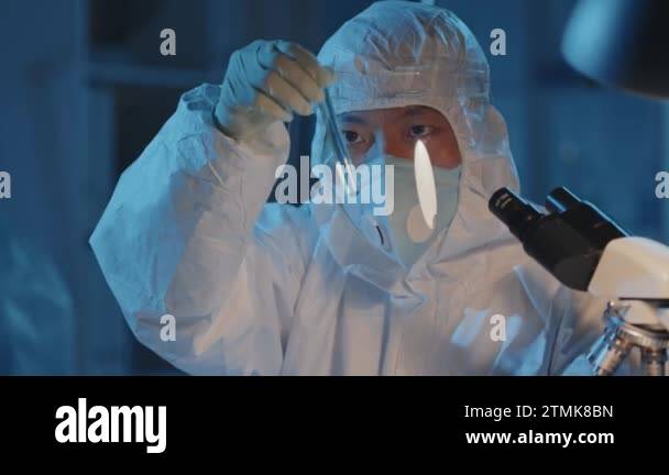 Chest-up of Asian scientist in white hazmat suit, respirator and face ...