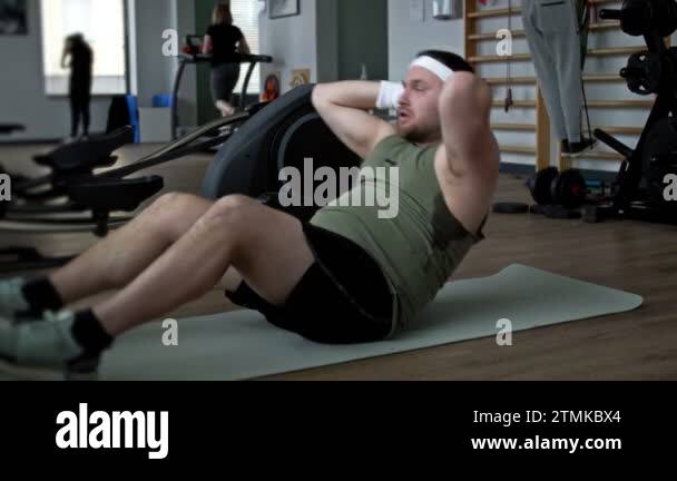 An overweight man is diligently pushing his abs while lying down on a ...