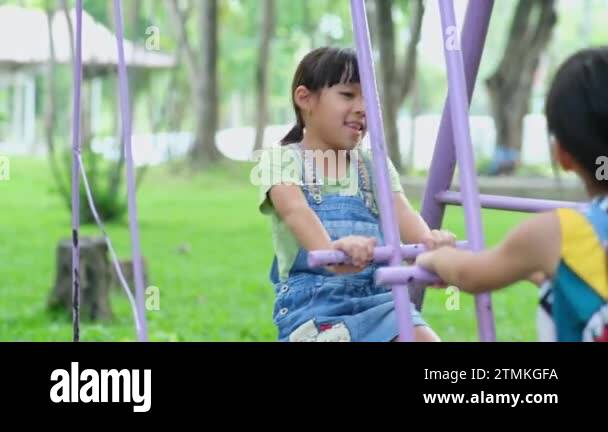 Two cute little sisters having fun playing in the playground during ...
