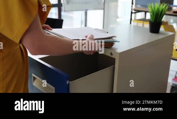 Female secretary in yellow dress puts stack of project documents into ...