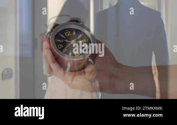 Animation of caucasian cropped hand holding alarm clock, diverse coworkers sharing ideas in ...