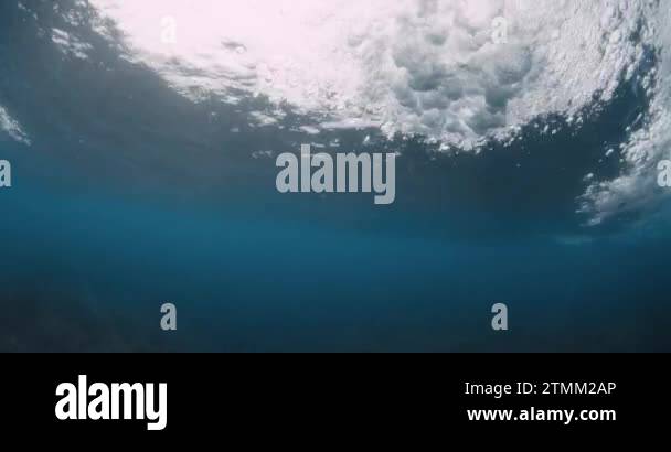 Breaking wave underwater in blue ocean. Underwater view of powerful ...