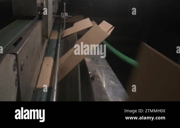 Automatic equipment folds carrying cardboard boxes in plant workshop ...