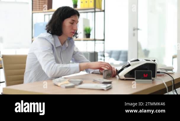 Man puts money in banknote counter and counts dollars in office ...