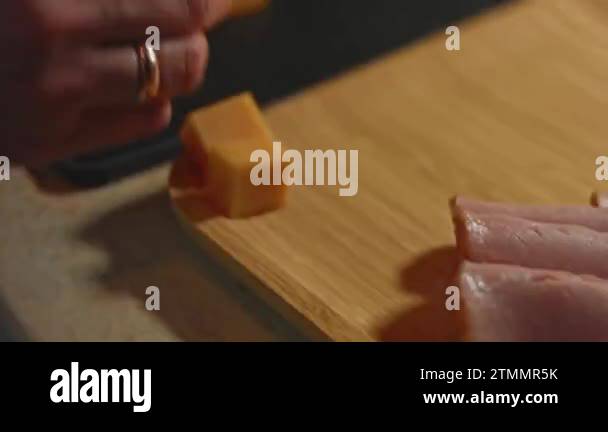 Cheddar cheese block being cut on a cutting board. Cubed cheddar cheese ...