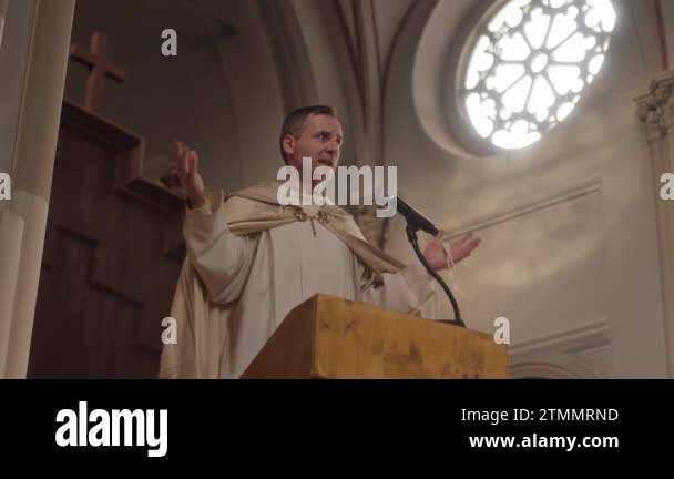Low angle medium slowmo of Caucasian priest in festive white alb ...