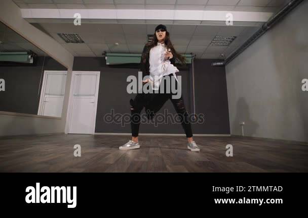 Young girl dancing modern dance in black clothes. Dancer makes a quick ...