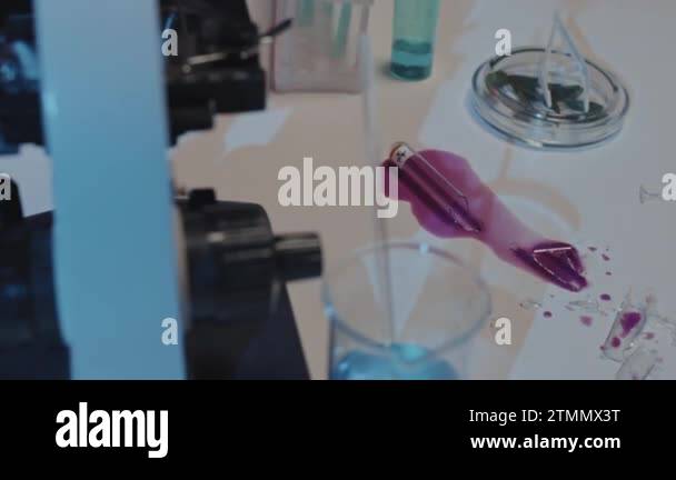 Top-down view of broken test tube with hazardous liquid on desk in ...