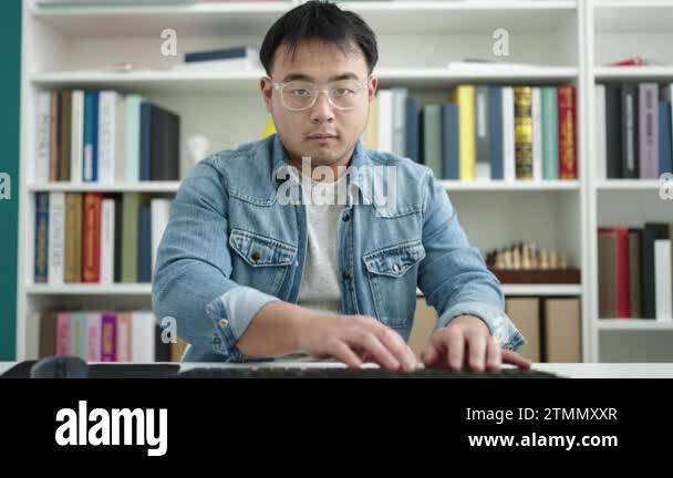 Young chinese man student using computer stressed at library university ...