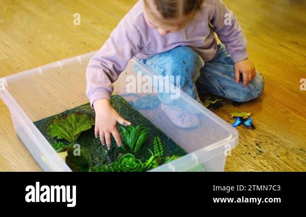 Little girl playing in handmade swamp of green-dyed chia seeds with ...