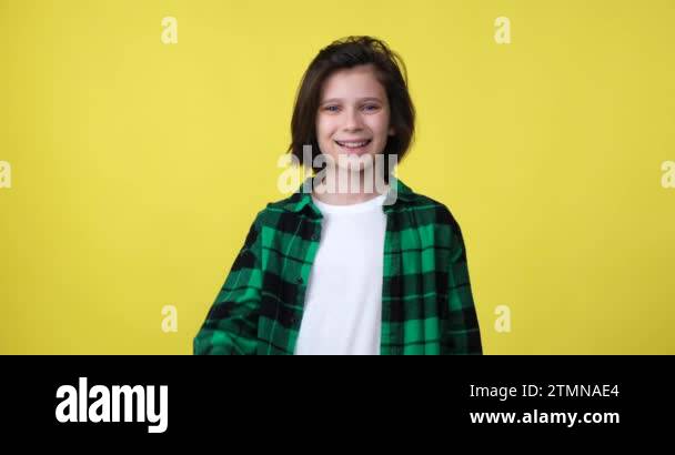 A cheerful young Caucasian boy stands on a yellow background and ...