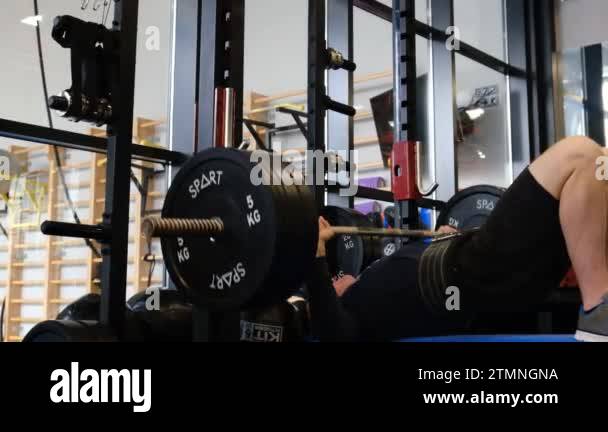 Barbell bench press. A young athlete on a simulator in a supine ...