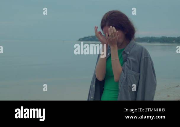 Young woman crying on the beach, looking sadly at the horizon in slow ...