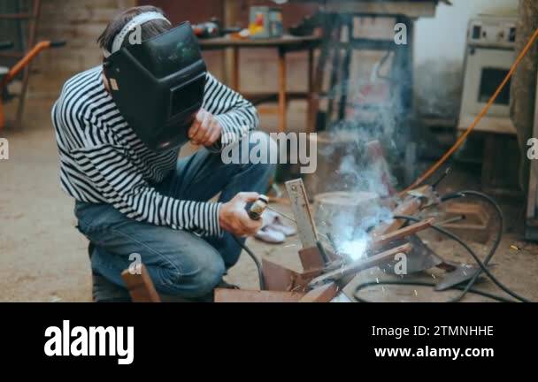 A welder welds a metal structure in the backyard of the estate. Using a ...