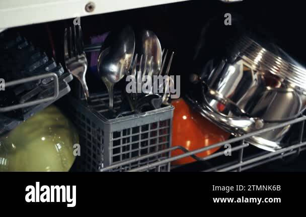 Loading dirty plates, crockery and glass into the dishwasher. Puts ...