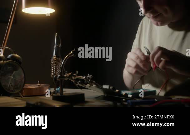 A person using a multimeter studies a microcircuit looking for an open ...