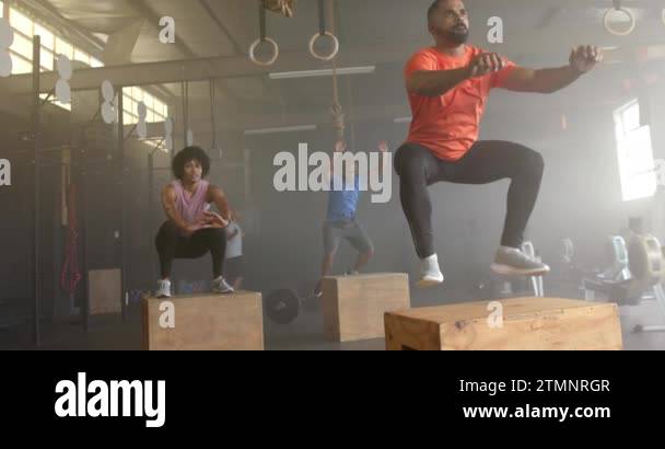 Diverse group fitness class jumping onto boxes, cross training at gym ...