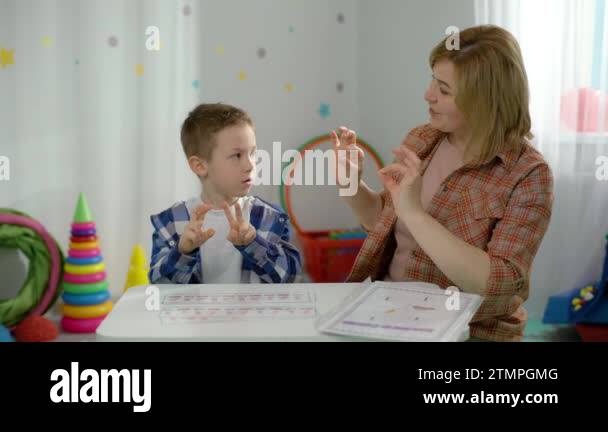 A Caucasian boy works with a speech therapist in the classroom. The ...