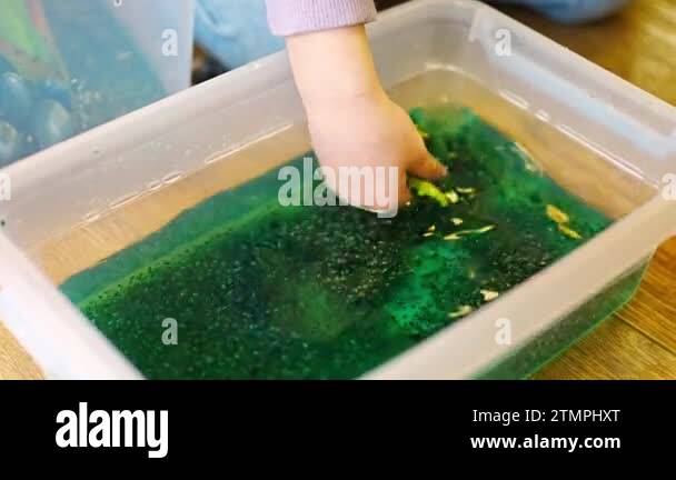 Little girl playing in handmade swamp of green-dyed chia seeds with ...