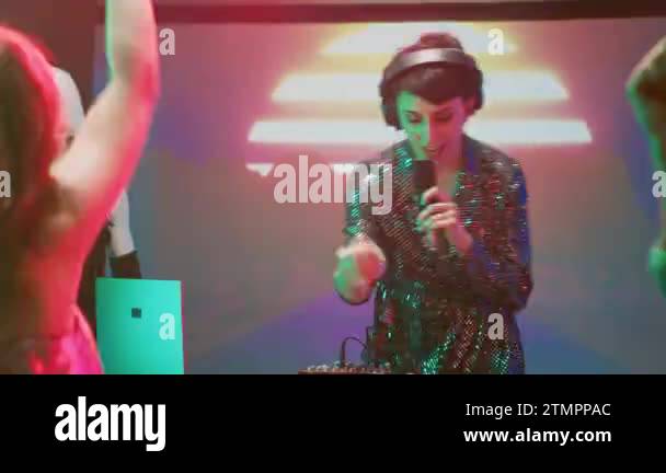 Female DJ mixing music at club on stage, partying with group of funky ...