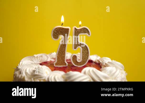 A candle in the form of the number 75, stuck in a holiday cake, is ...