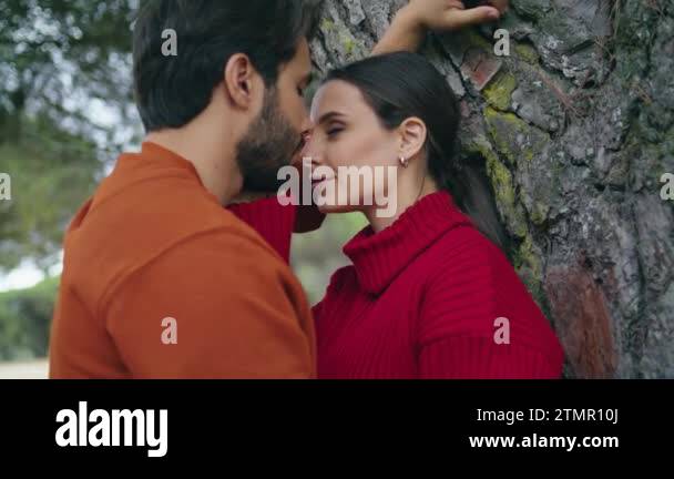 Portrait of loving romantic couple standing near forest tree looking on ...