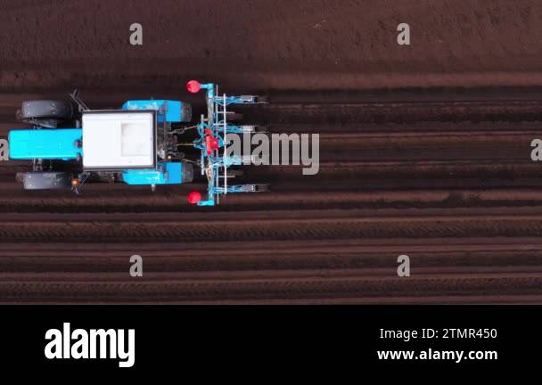 Tractor sowing seeds with a seeder driller in a field. Top view of ...
