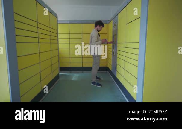 Man uses yellow packing station to send package by self-service. German ...