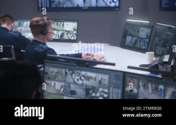 Diverse employees work in security control center, watch CCTV cameras with AI face scanning ...