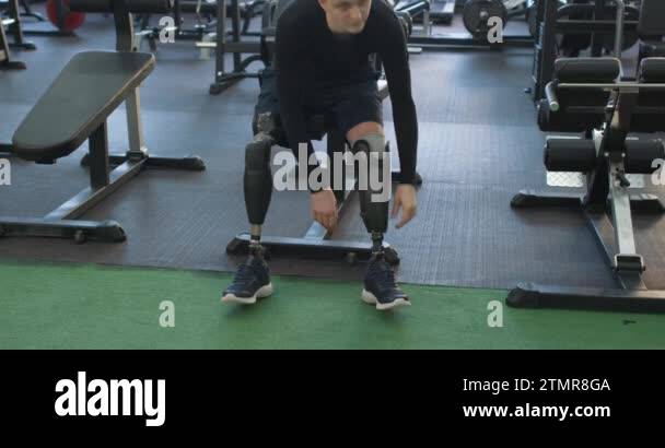 Disabled young man with prosthetic amputee legs sitting at gym Slow ...
