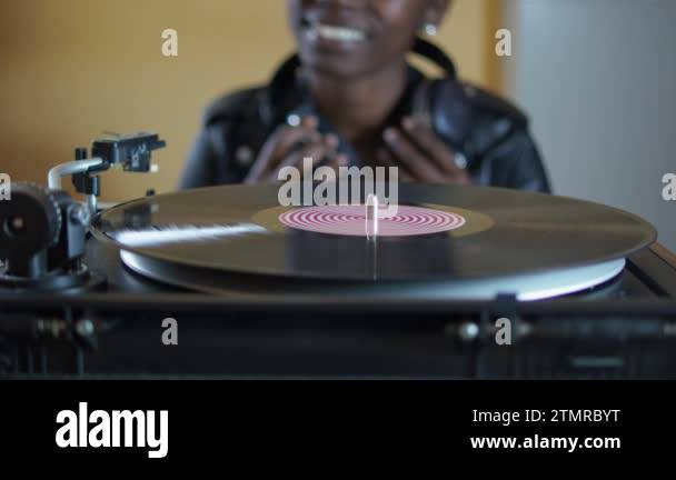 young woman wearing a leather jacket using headphones while playing a ...