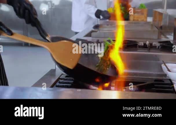 Closeup hands of chef man stir frying morning glory fire flame with ...