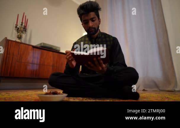 Young intelligent Middle Eastern man reading book eating dried fruits ...