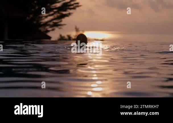 A video of a boy swimming at the infinity pool during sunset in ...