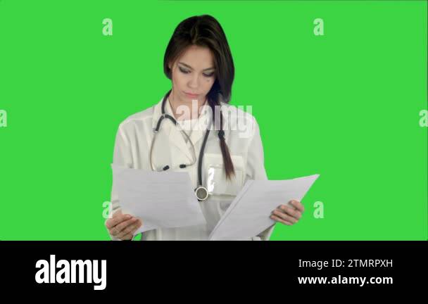 Young female doctor reading patient medical history forms on a Green ...
