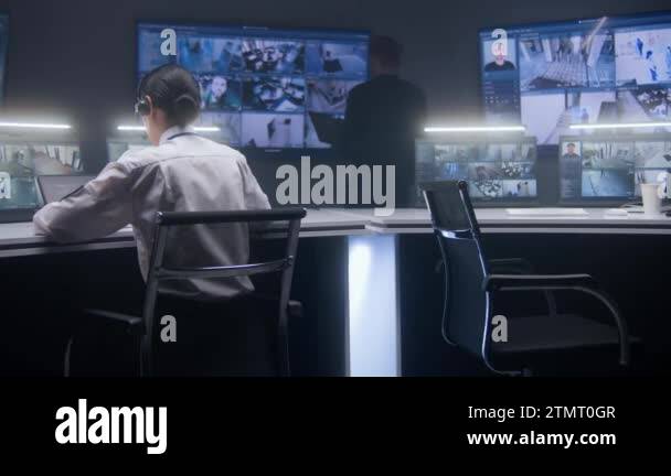 Multi ethnic security employees monitor CCTV cameras in police ...